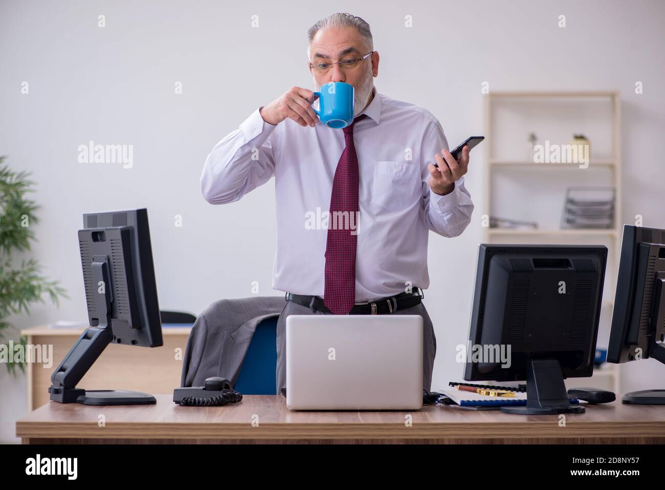 Old boss sitting at desktop in the office Stock Photo - Alamy