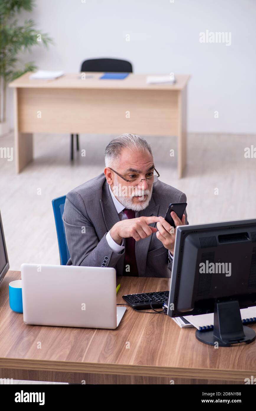 Old boss sitting at desktop in the office Stock Photo - Alamy