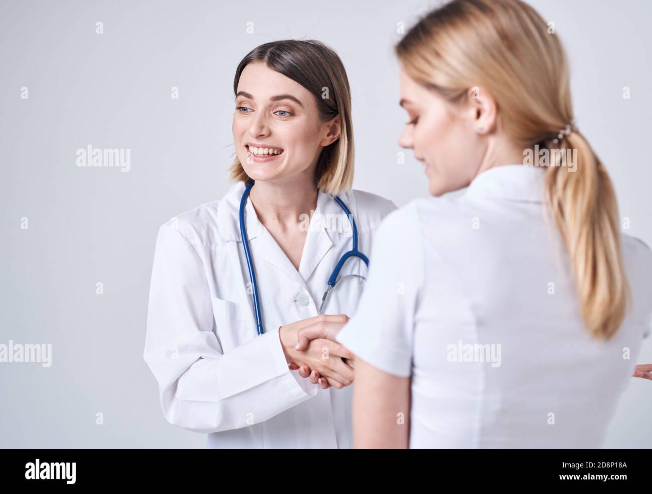 Happy woman doctor in medical gown with stethoscope and patient back ...