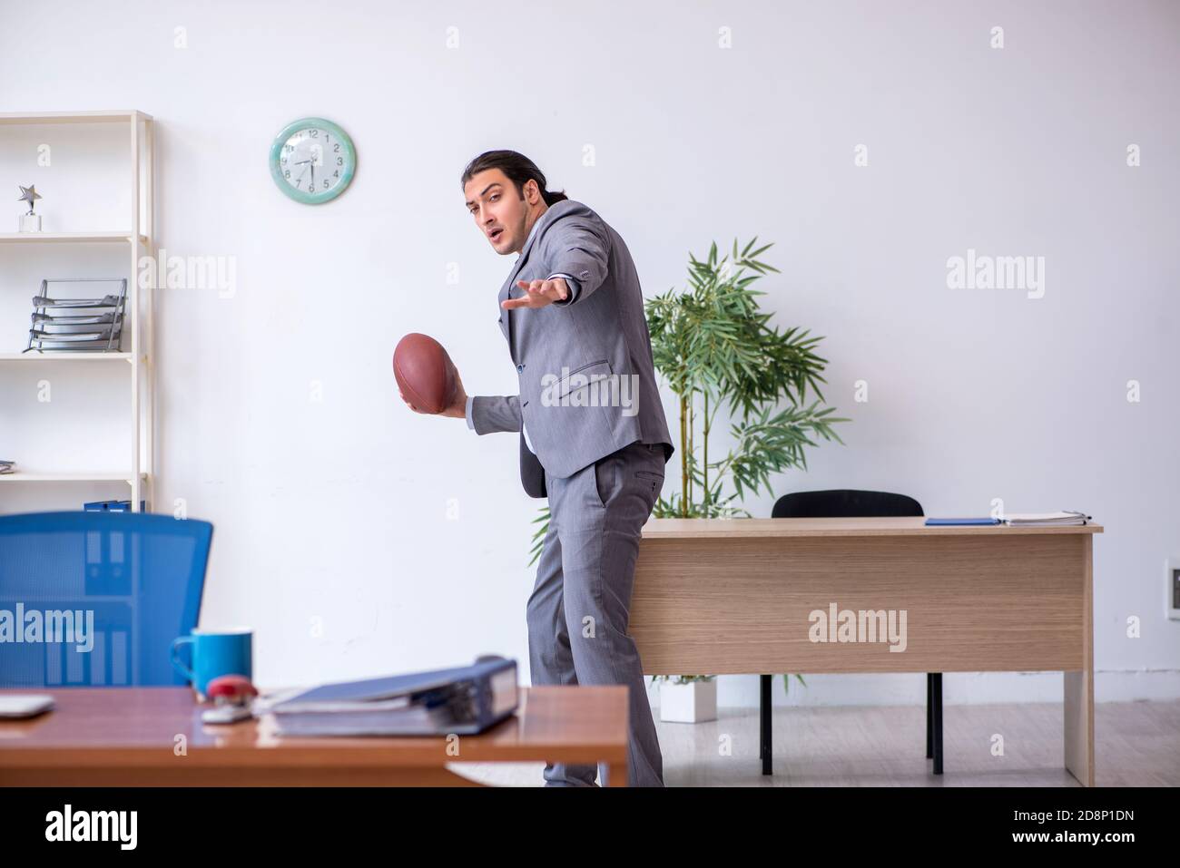 Male employee with rugby ball in the office Stock Photo - Alamy