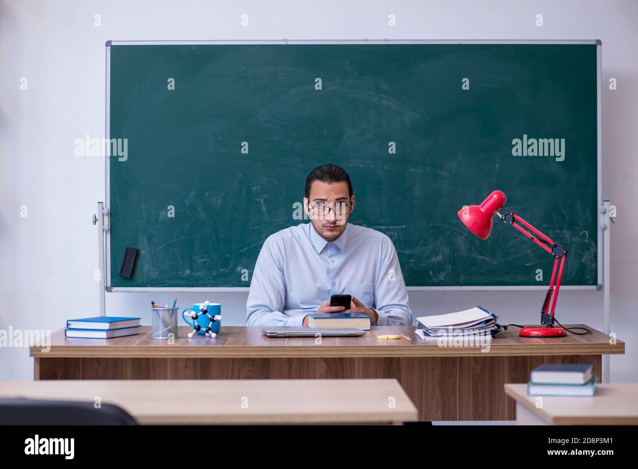 Young teacher in front of green board Stock Photo - Alamy