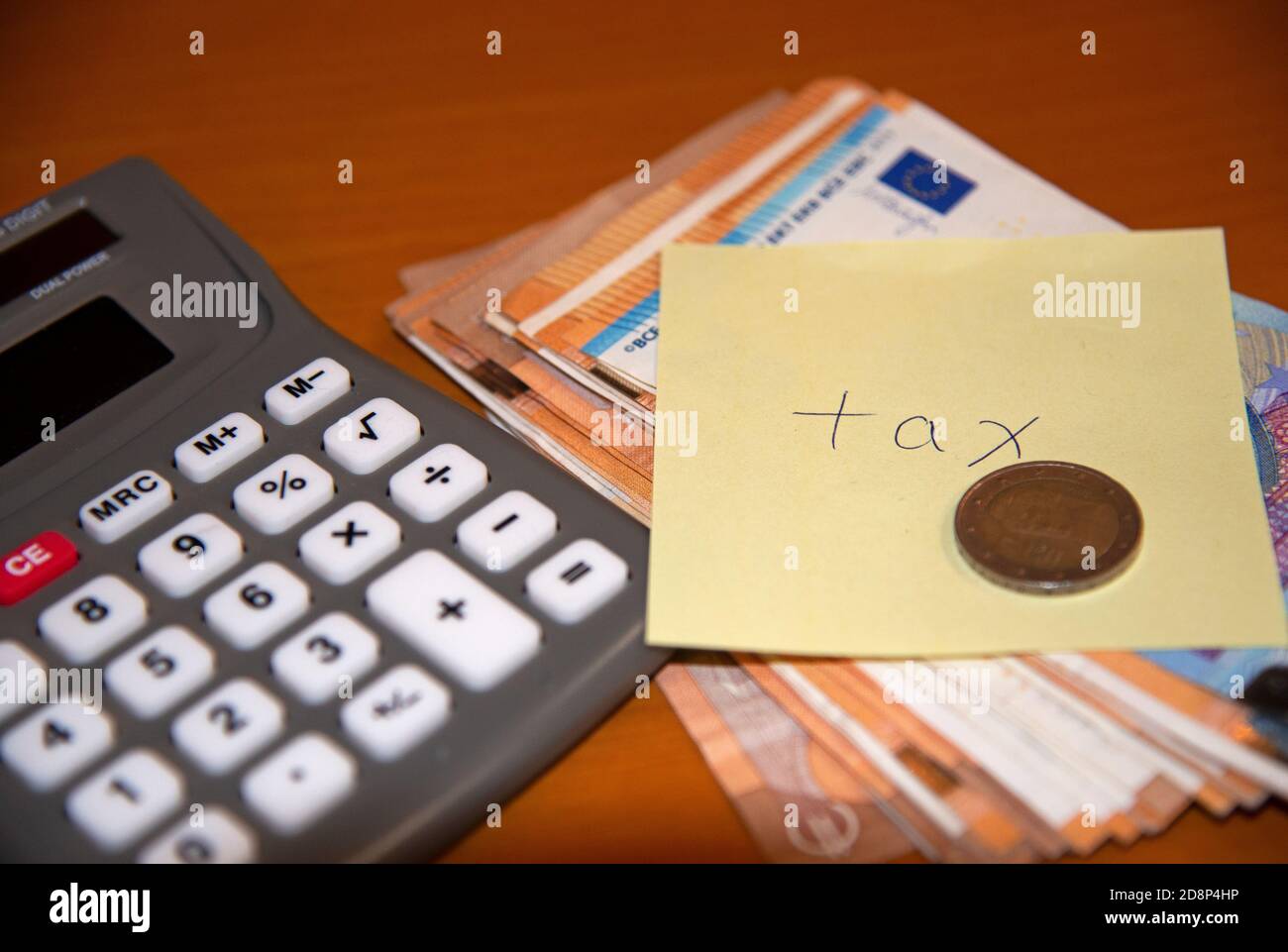 Income tax written on post-it note with bank notes, a coin and a ...