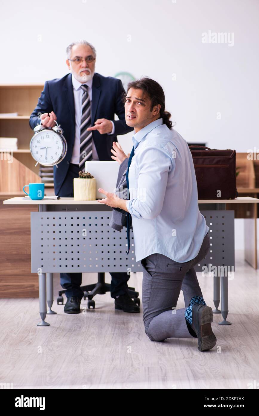 Old boss and young male employee in time management concept Stock Photo ...