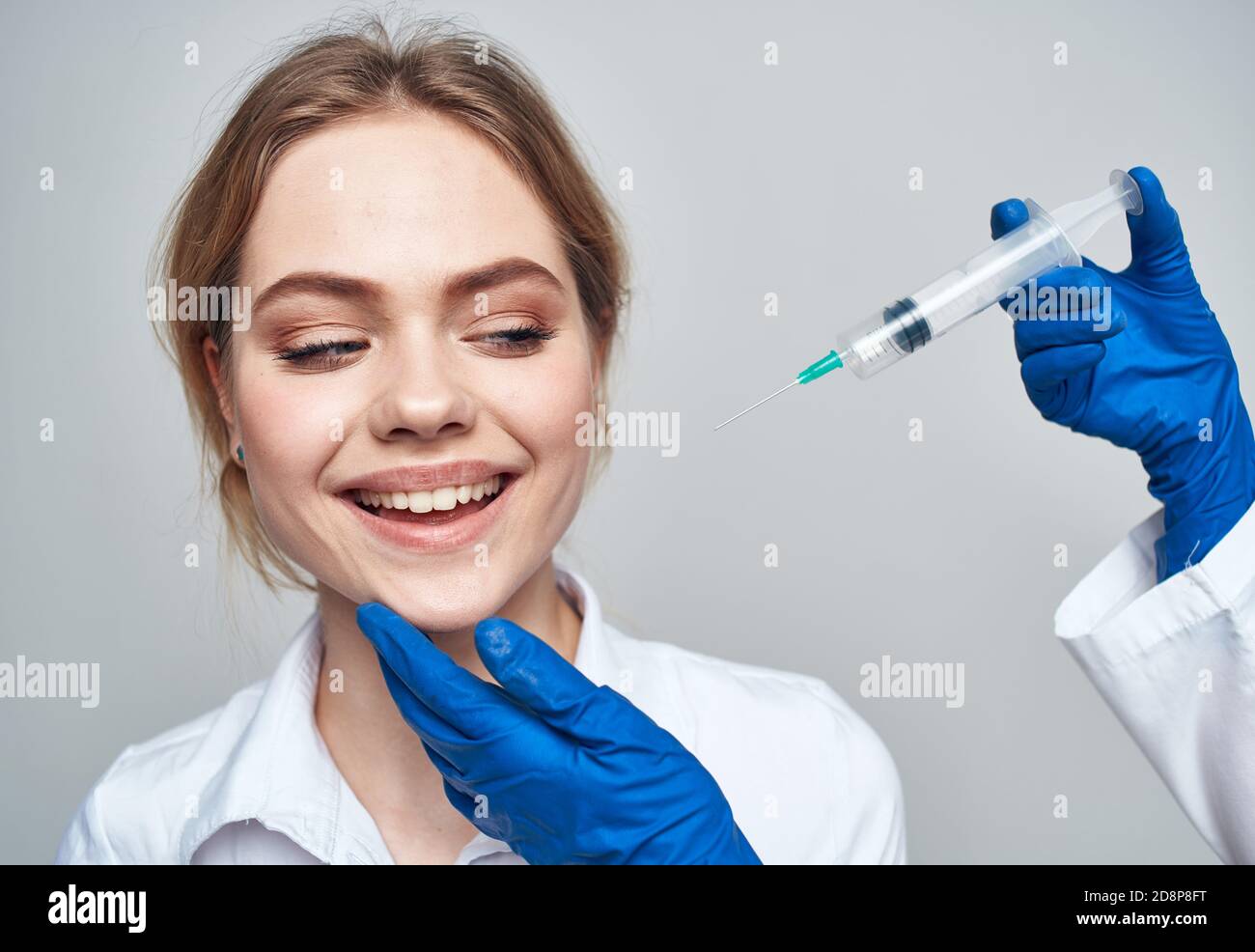 female patient smiling and a syringe in the hands of the doctor botox ...