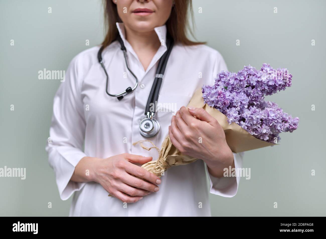Bouquet of lilac flowers in the hands of female doctor with stethoscope ...
