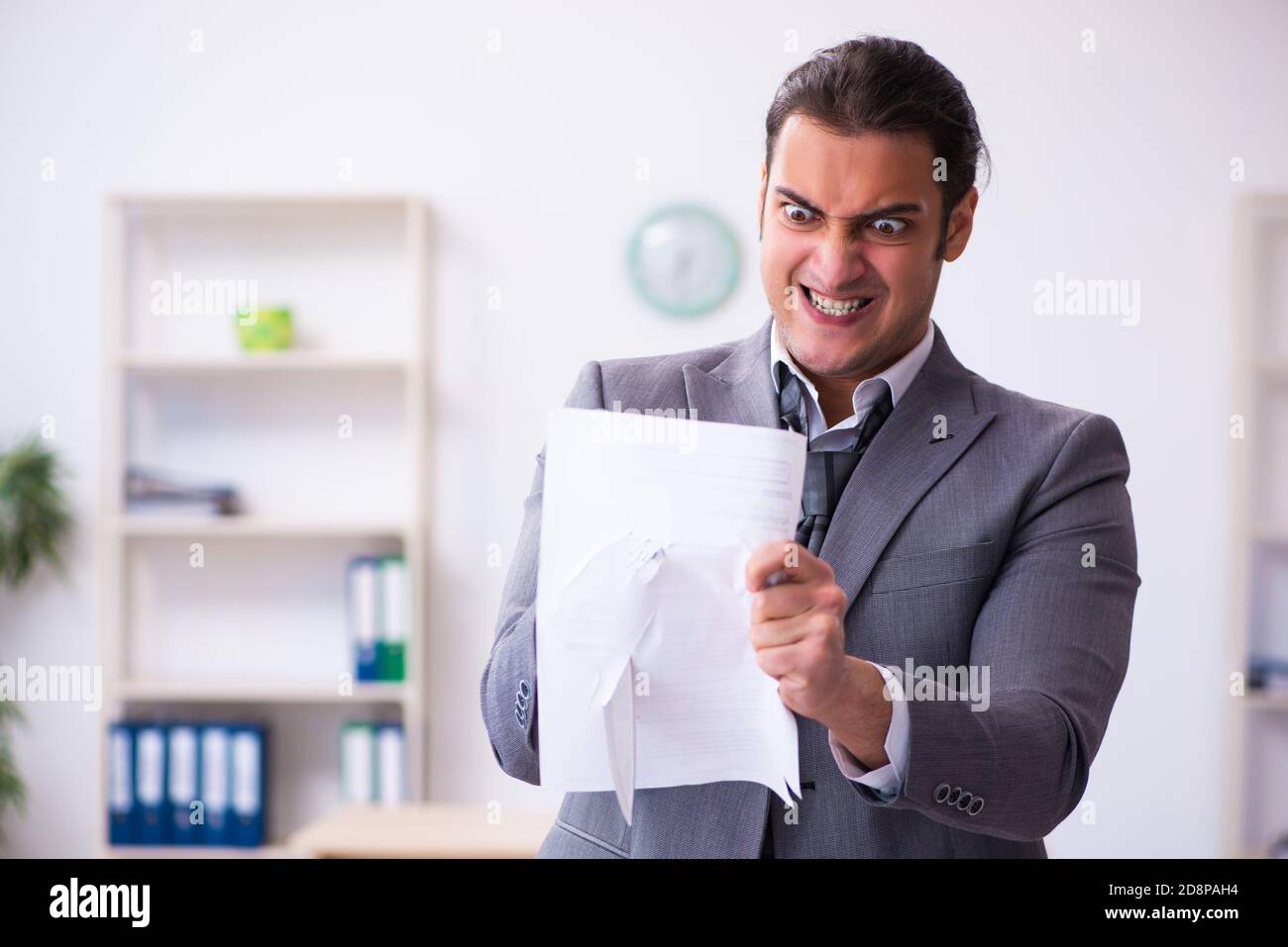 Male employee angry with excessive work holding knife Stock Photo - Alamy