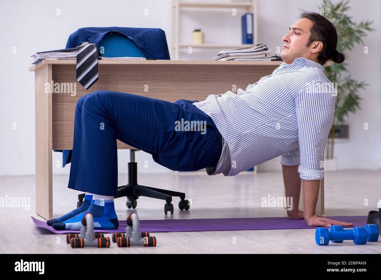 Handsome male employee doing exercises in the office Stock Photo - Alamy
