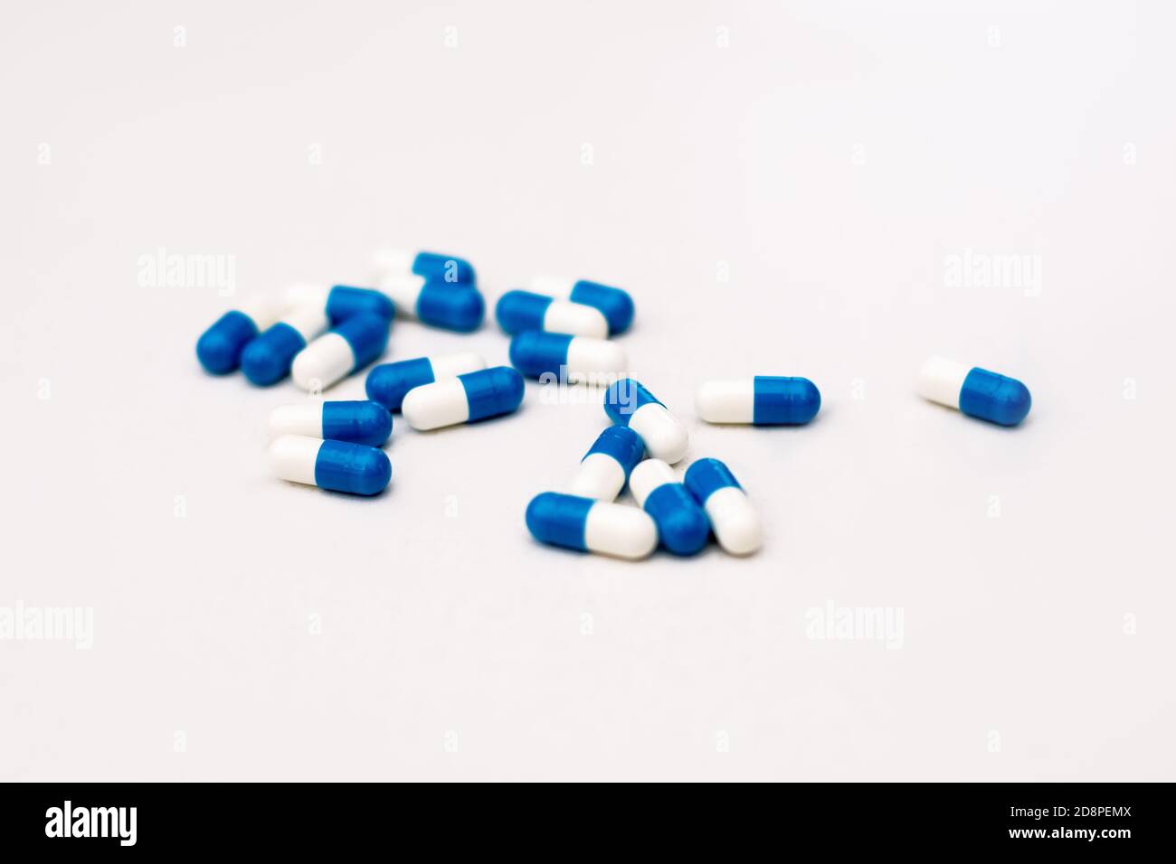 Photo close-up of blue medical capsules grouped in center on a white ...