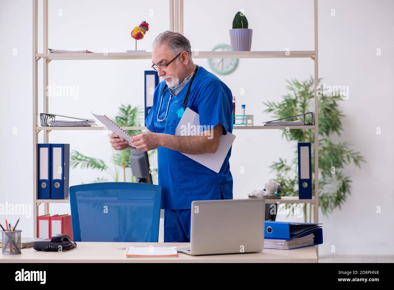 Old male doctor working in clinic Stock Photo - Alamy