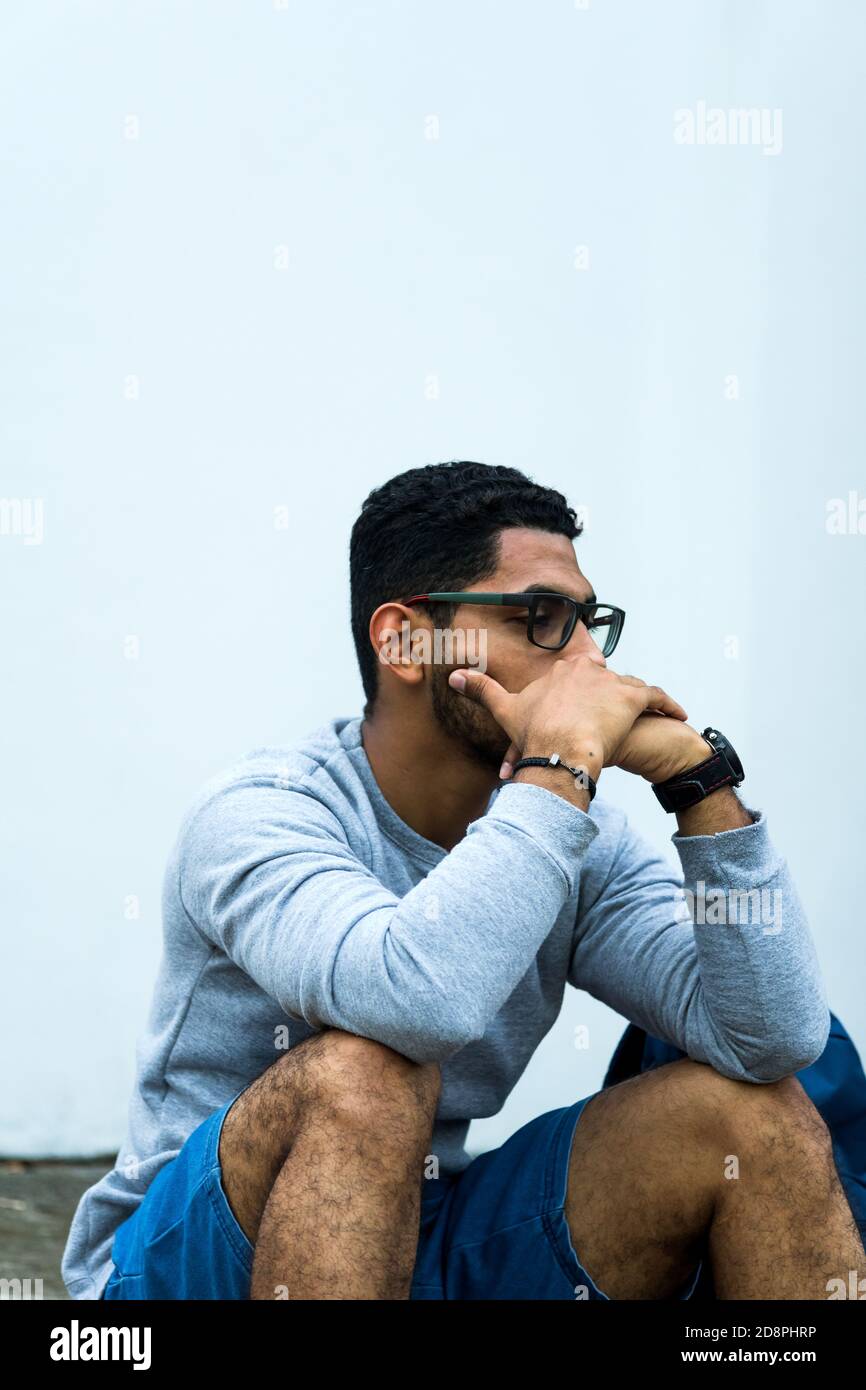 Vertical shot of a Latin man sitting on stairs looking sad and ...
