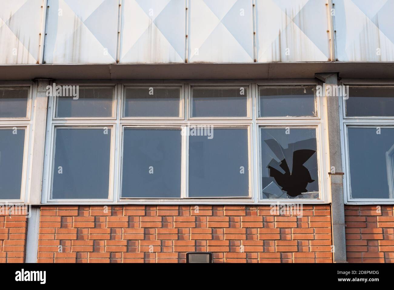 Smashed glass on a broken window on an abandoned and decaying factory industrial building left ...