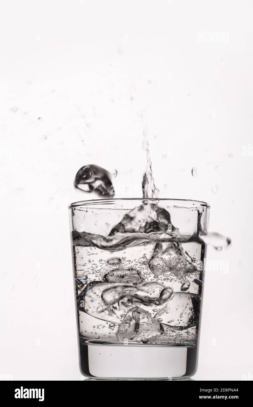 Crystals of ice falling into the glass of water Stock Photo - Alamy