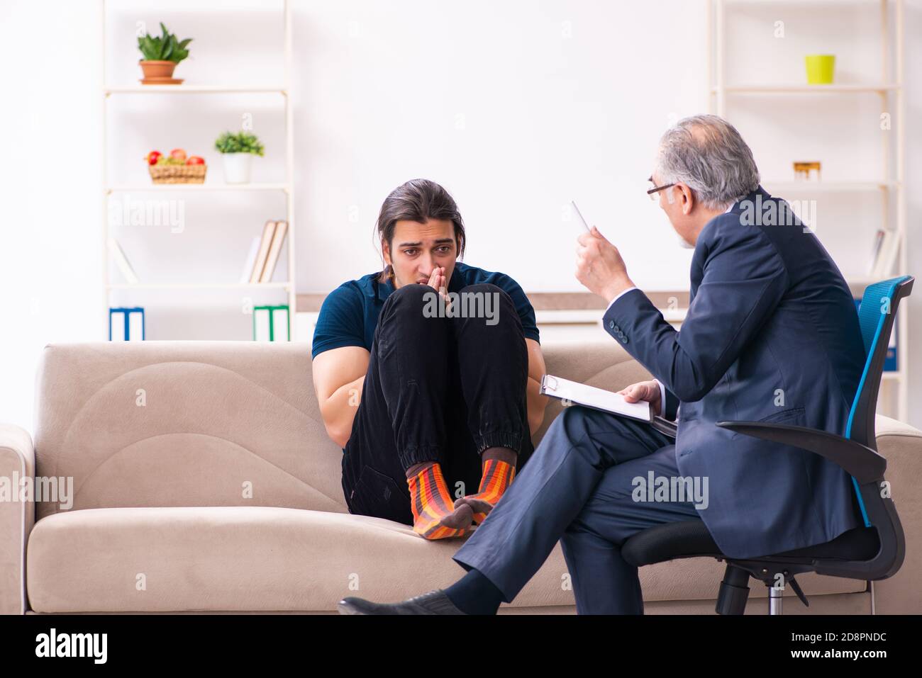 Young man visiting old psychologist Stock Photo - Alamy