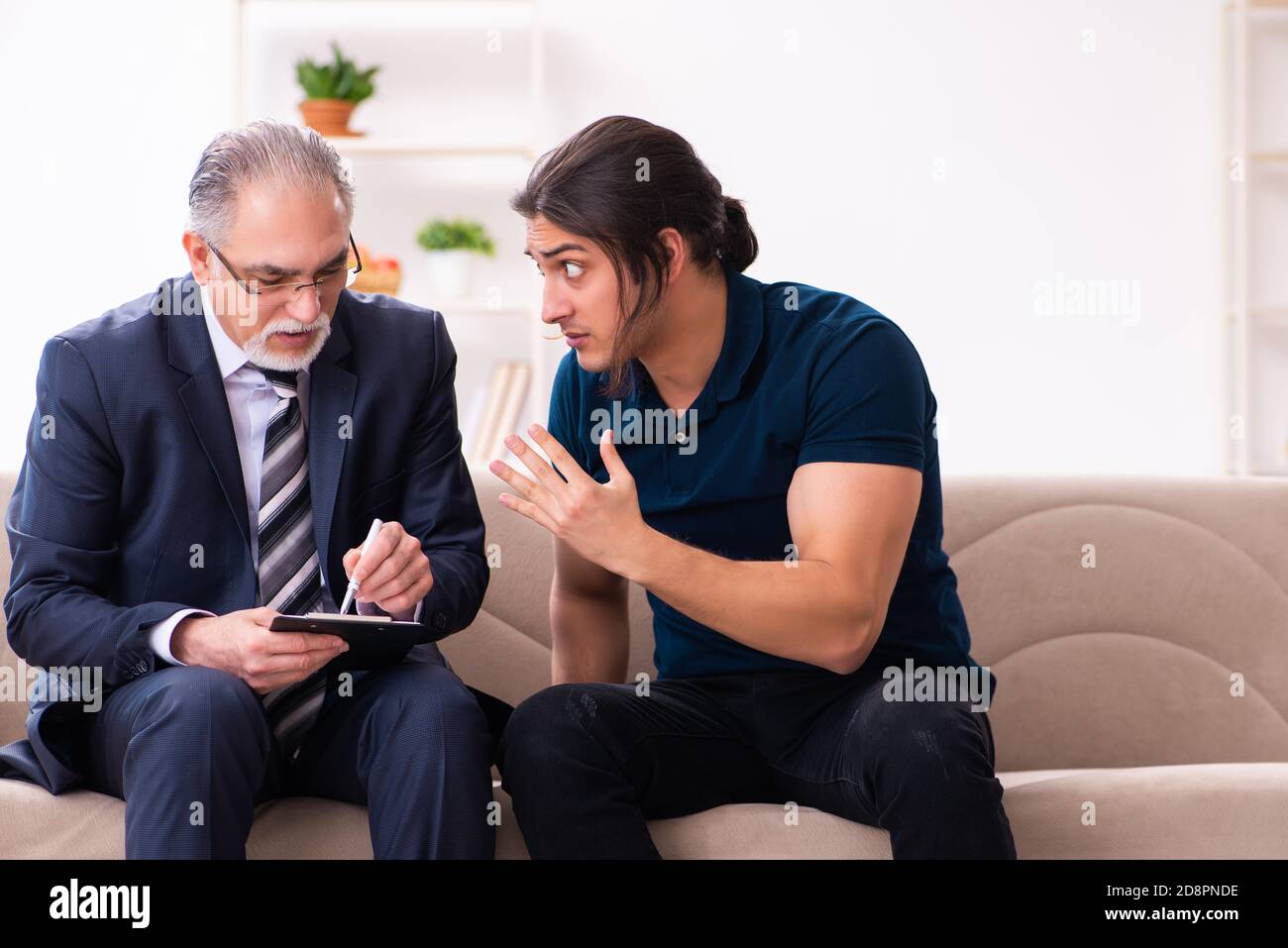 Young man visiting old psychologist Stock Photo - Alamy