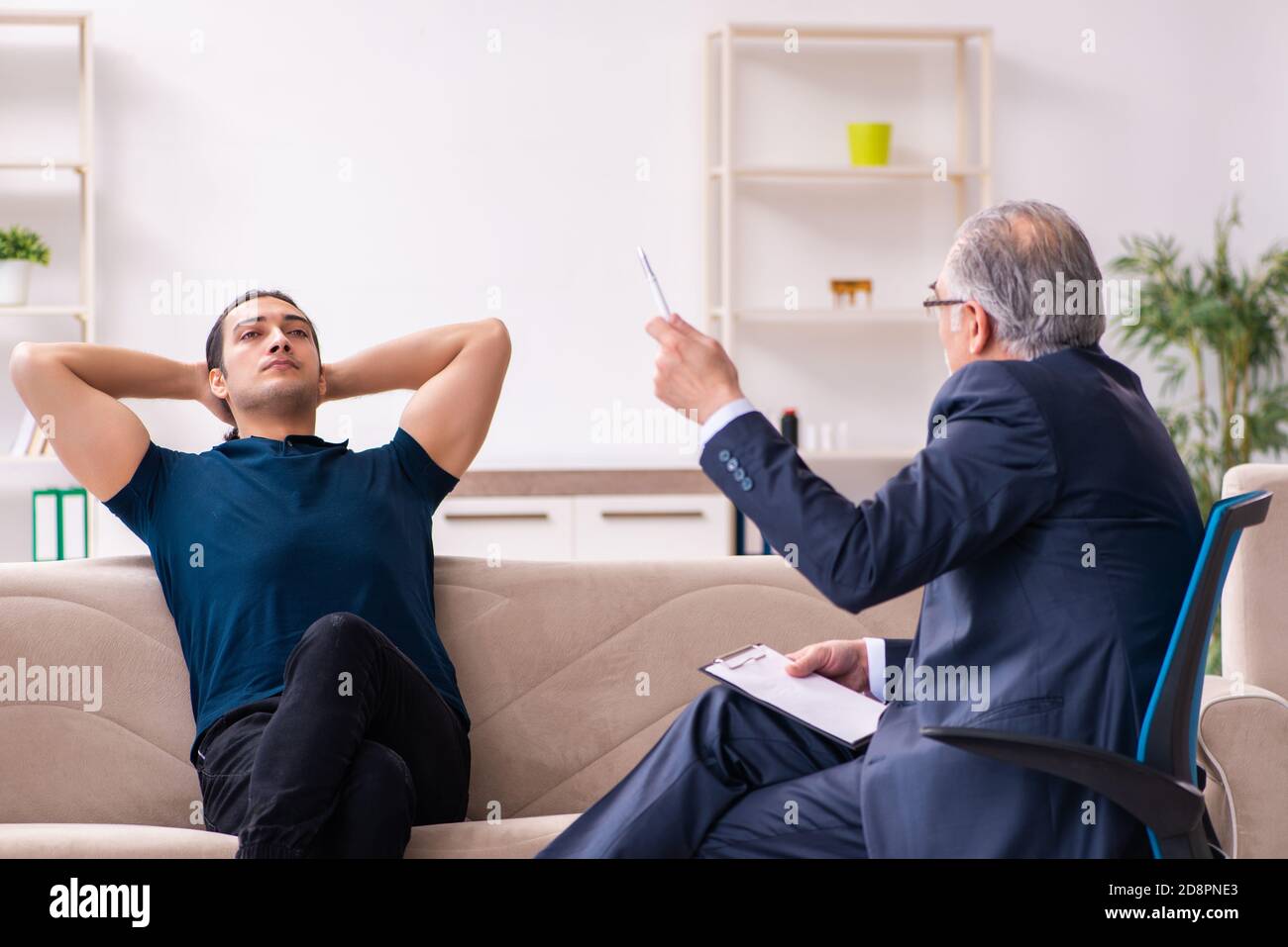 Young man visiting old psychologist Stock Photo - Alamy