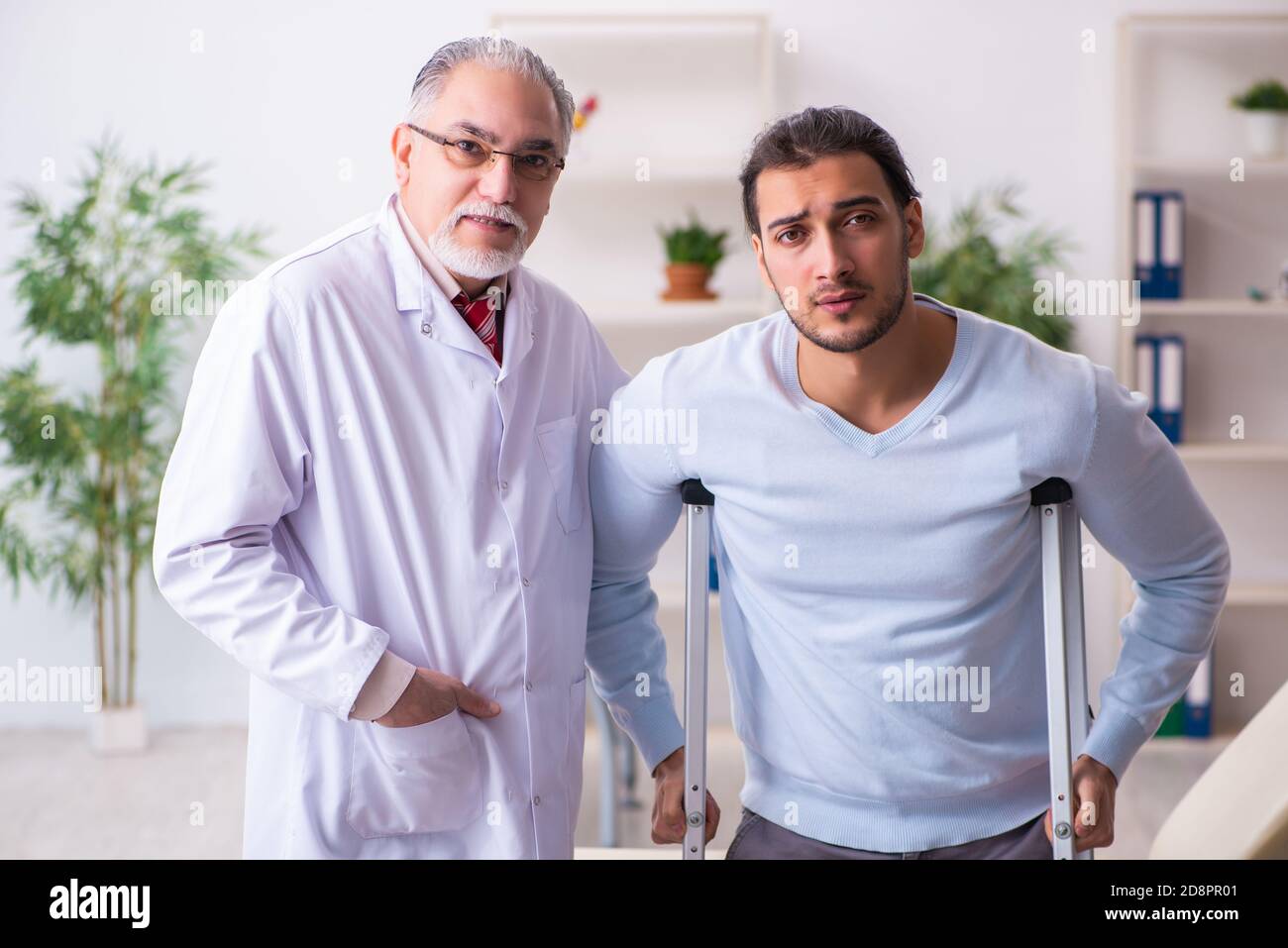 Leg injured man visiting old doctor osteopath Stock Photo - Alamy