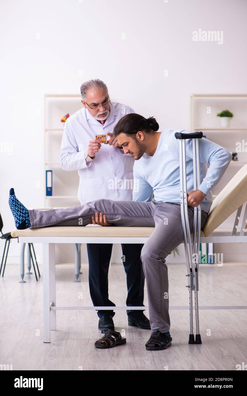 Leg injured man visiting old doctor osteopath Stock Photo - Alamy