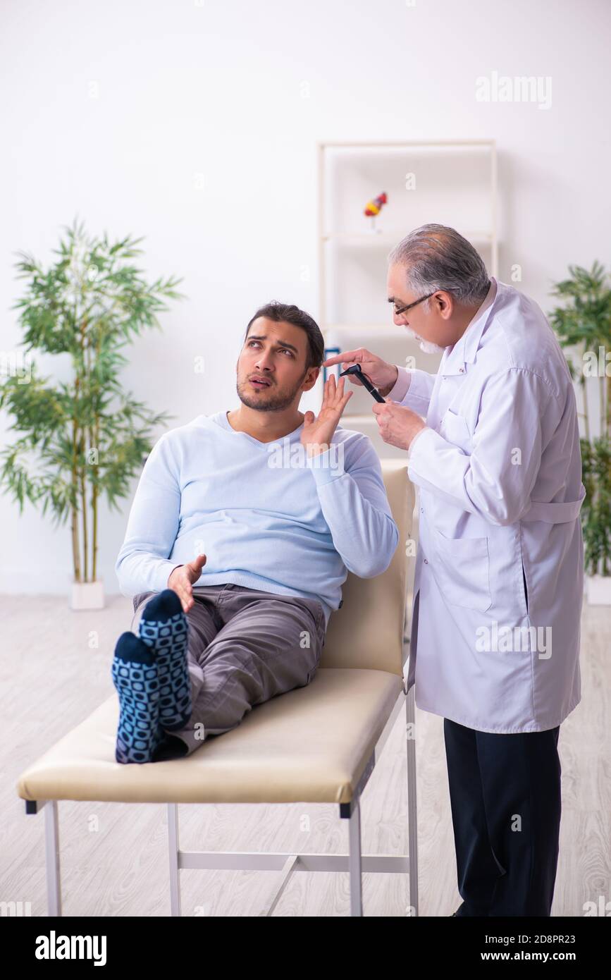 Sick man visiting old doctor otolaryngologist Stock Photo - Alamy