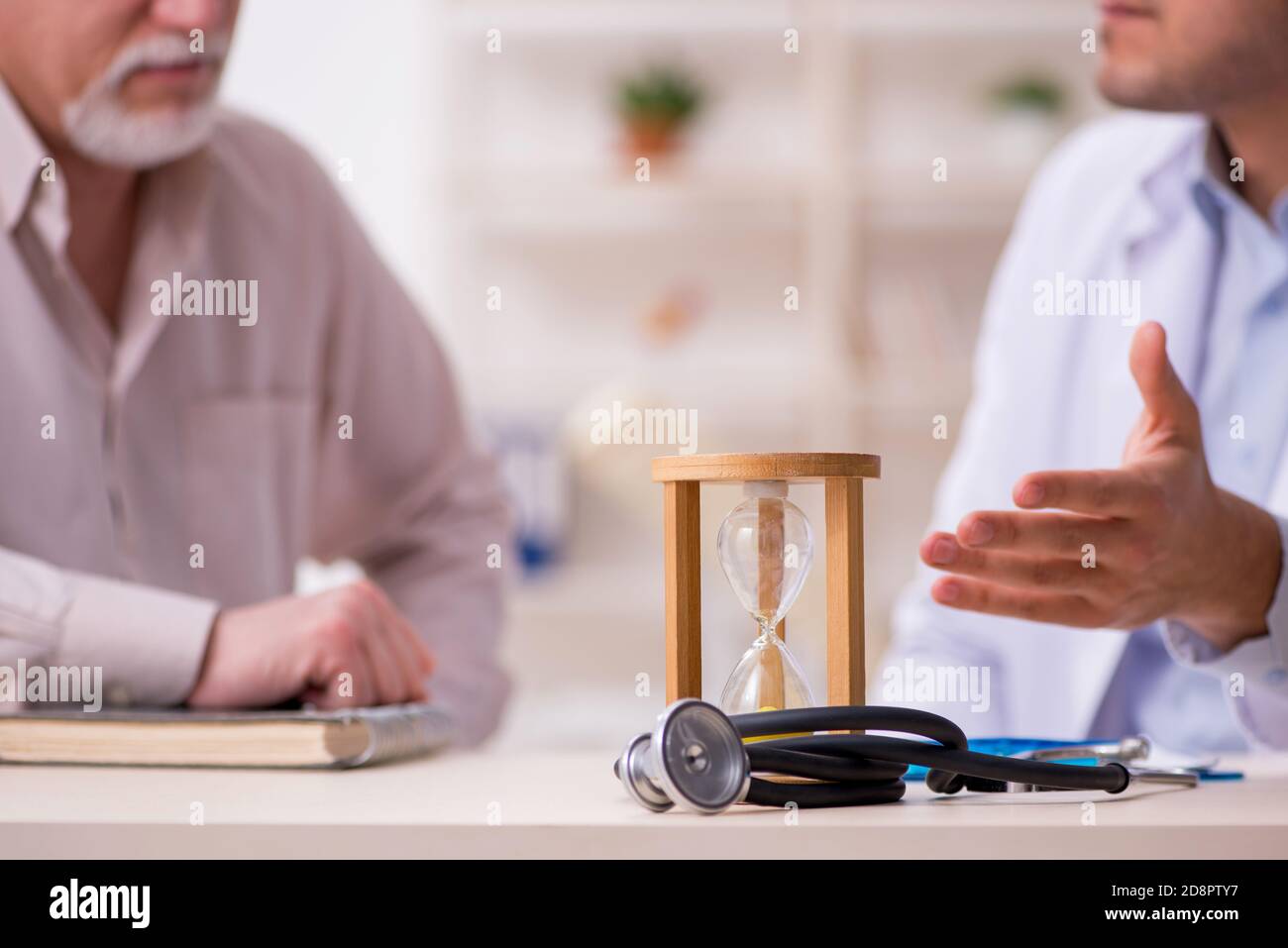 Old male patient visiting young doctor in time management concept Stock ...