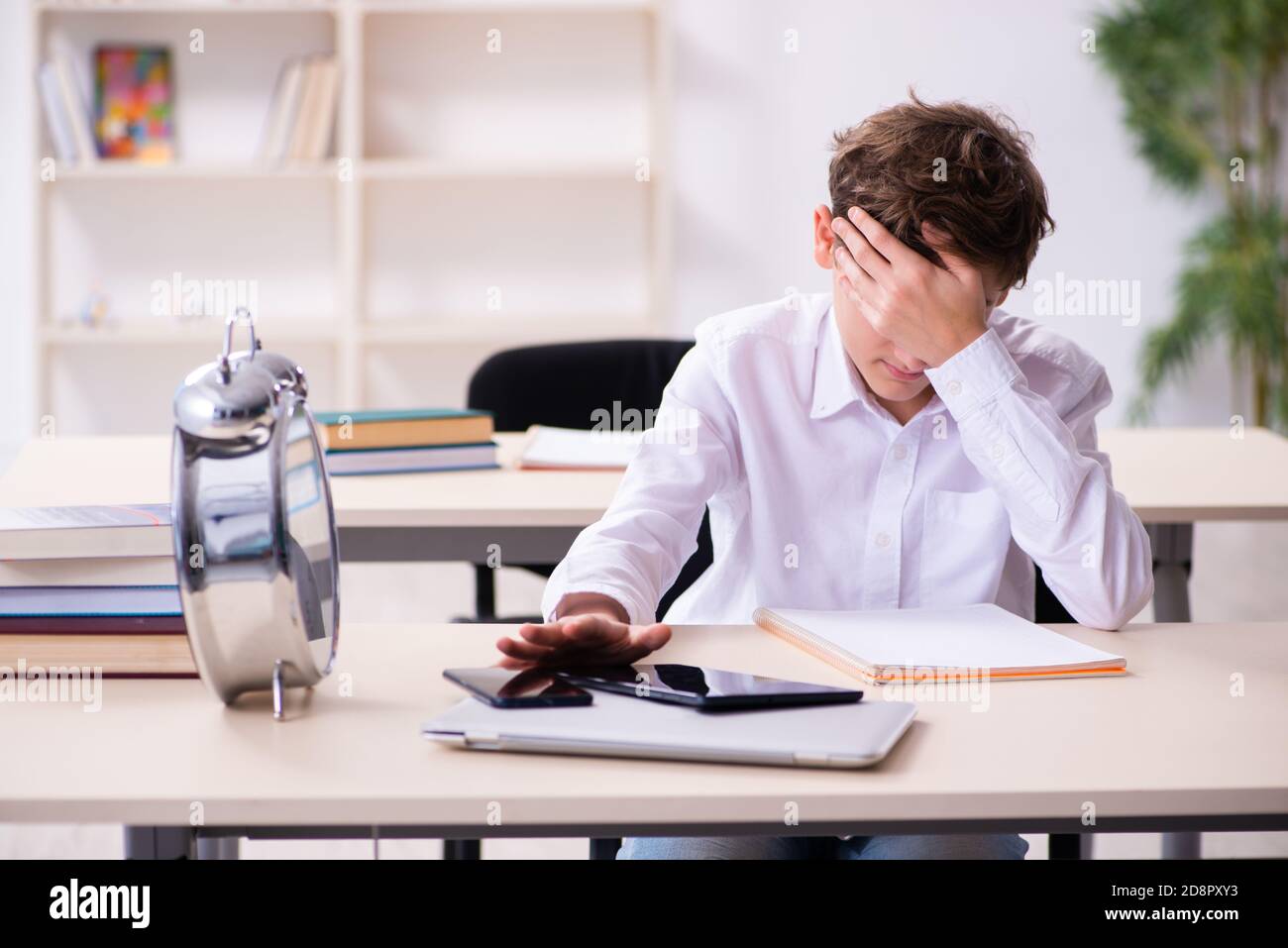 Schoolboy in punctuality concept in the classroom Stock Photo - Alamy