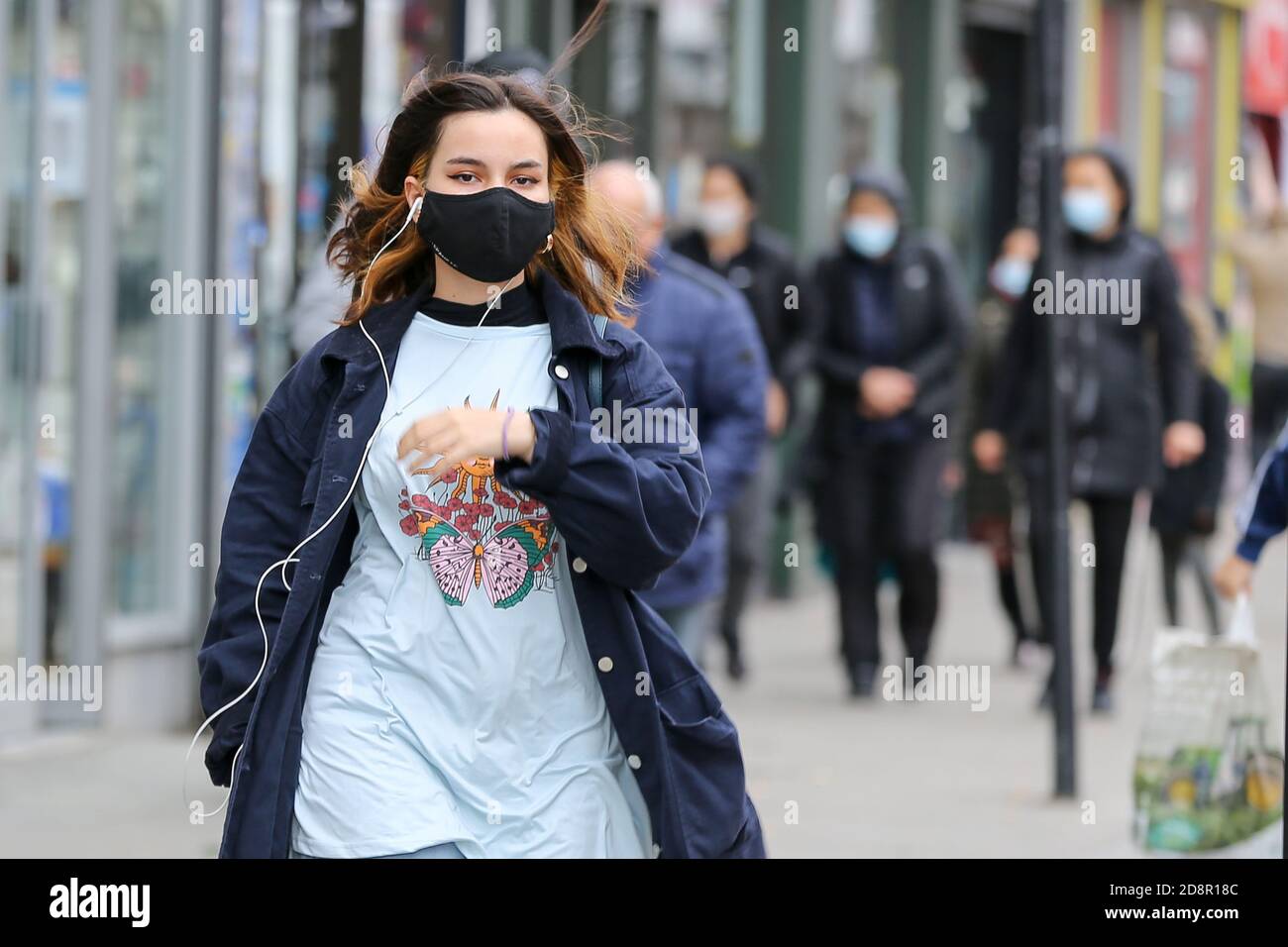 A woman wearing a face mask as a preventive measure walks on the street ...