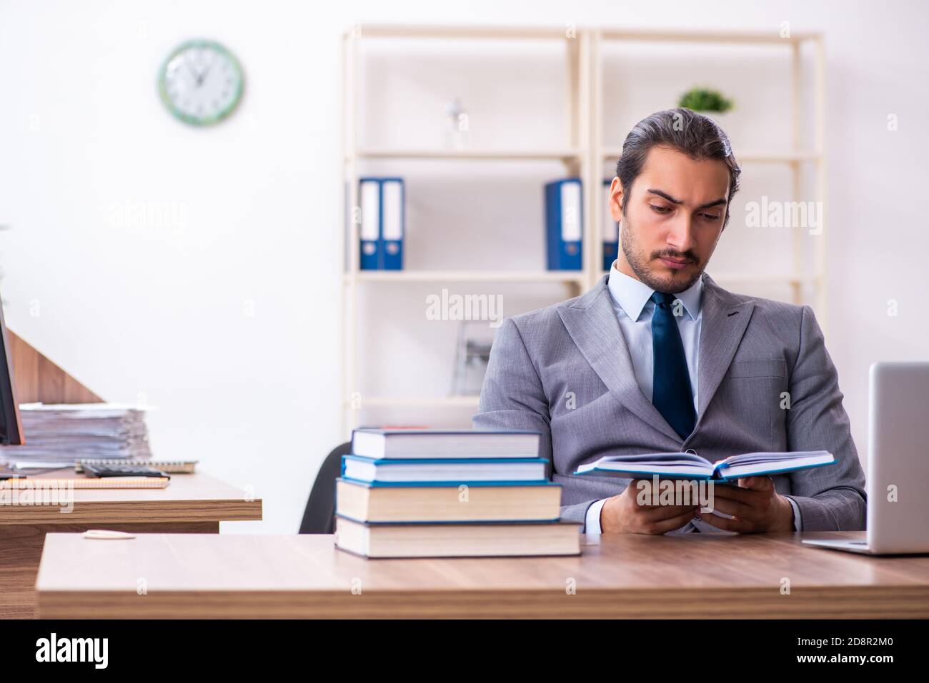 Young businessman reading books at workplace Stock Photo - Alamy