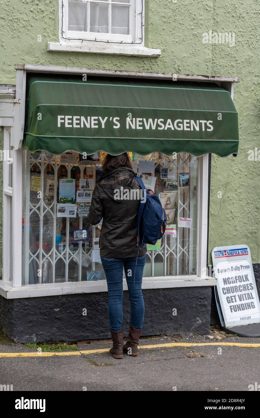 a young woman wearing a raincoat carrying a shoulder bag looking in the ...
