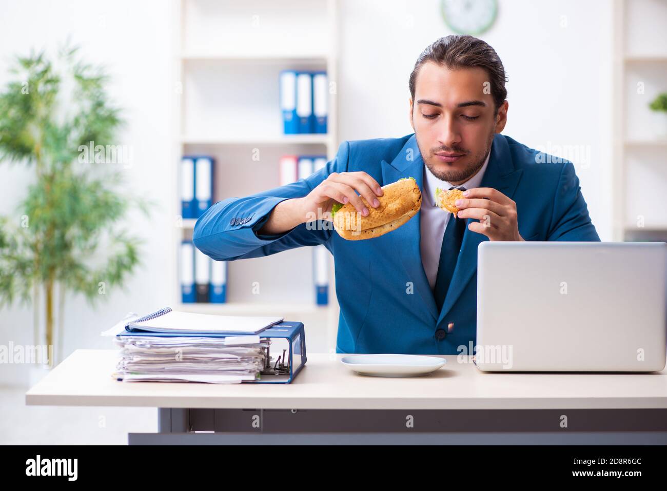 Young employee having breakfast at workplace Stock Photo - Alamy