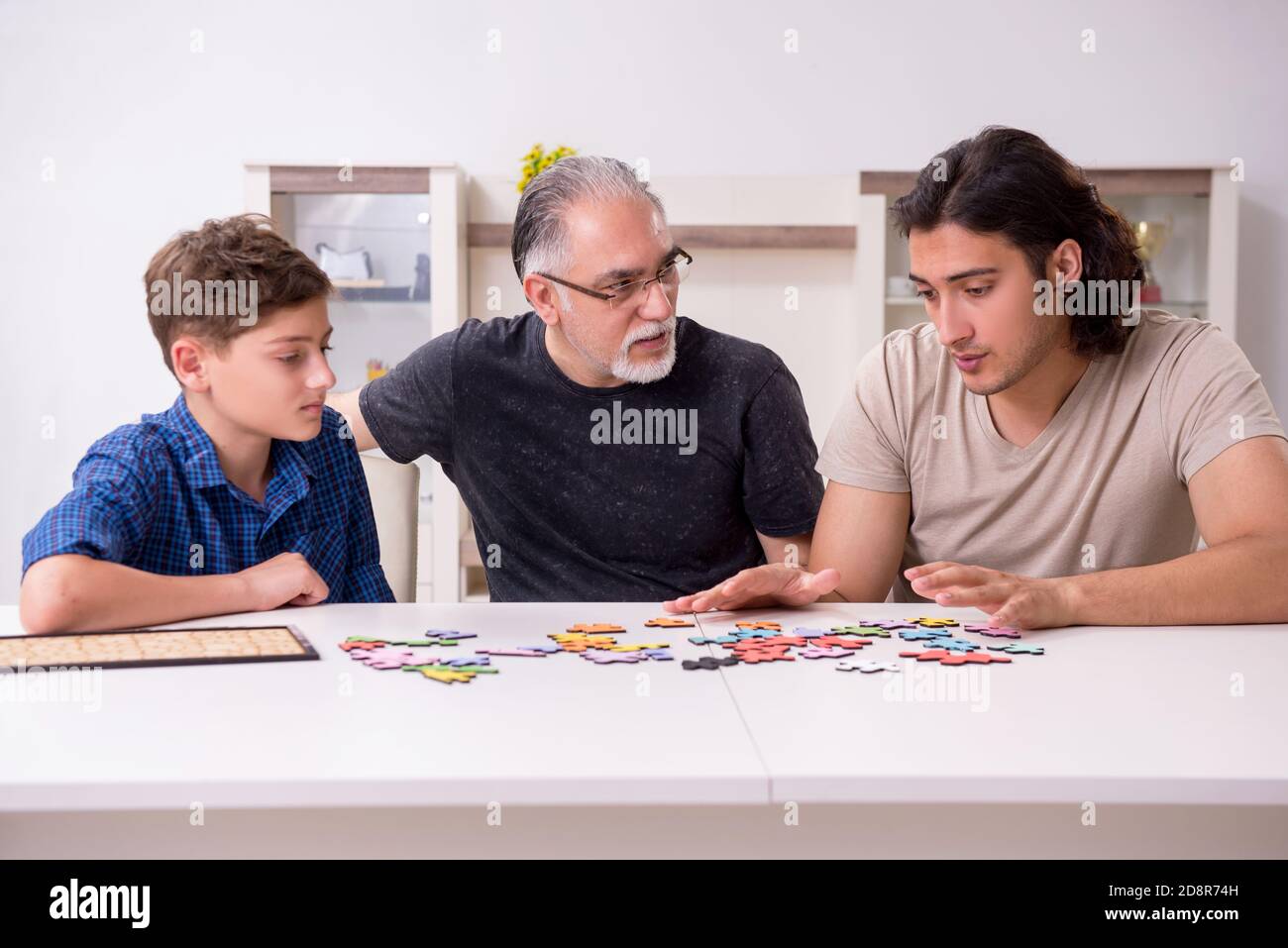 Three generations of family playing jigsaw puzzle Stock Photo - Alamy