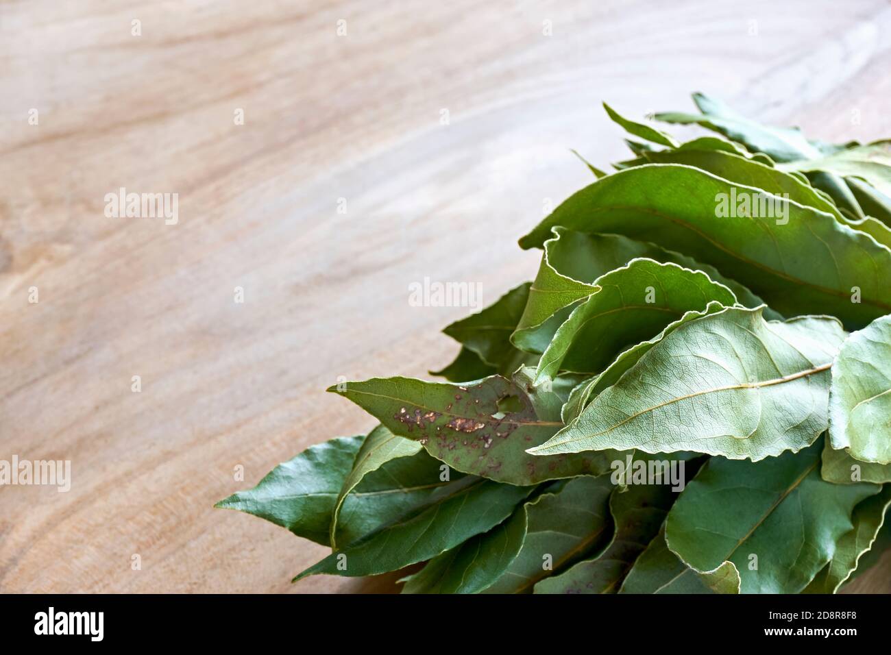 Dry green bay leaves on a wooden background. Also named Laurel or ...