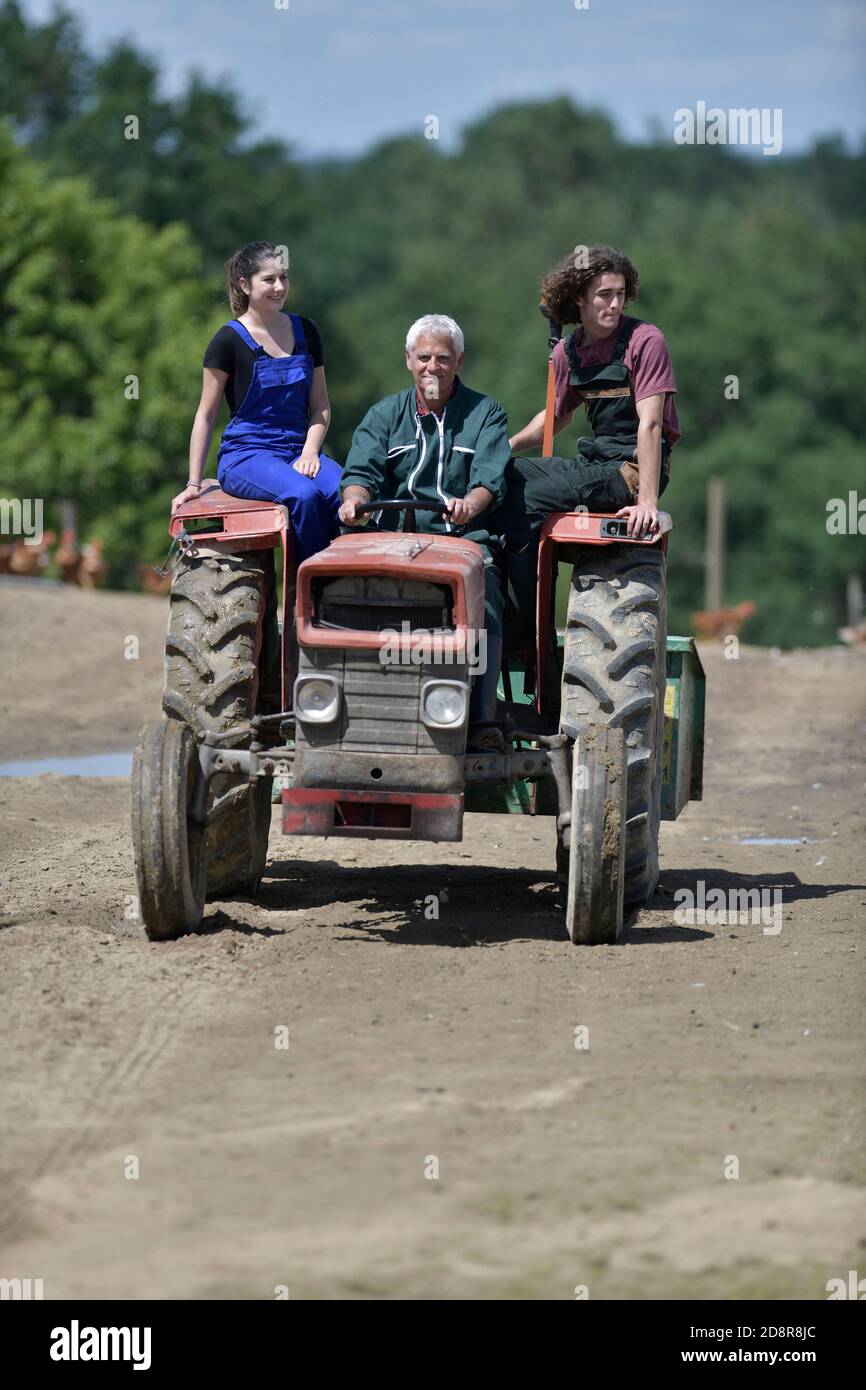 Farmer with apprentice riding tractor in farmland Stock Photo - Alamy