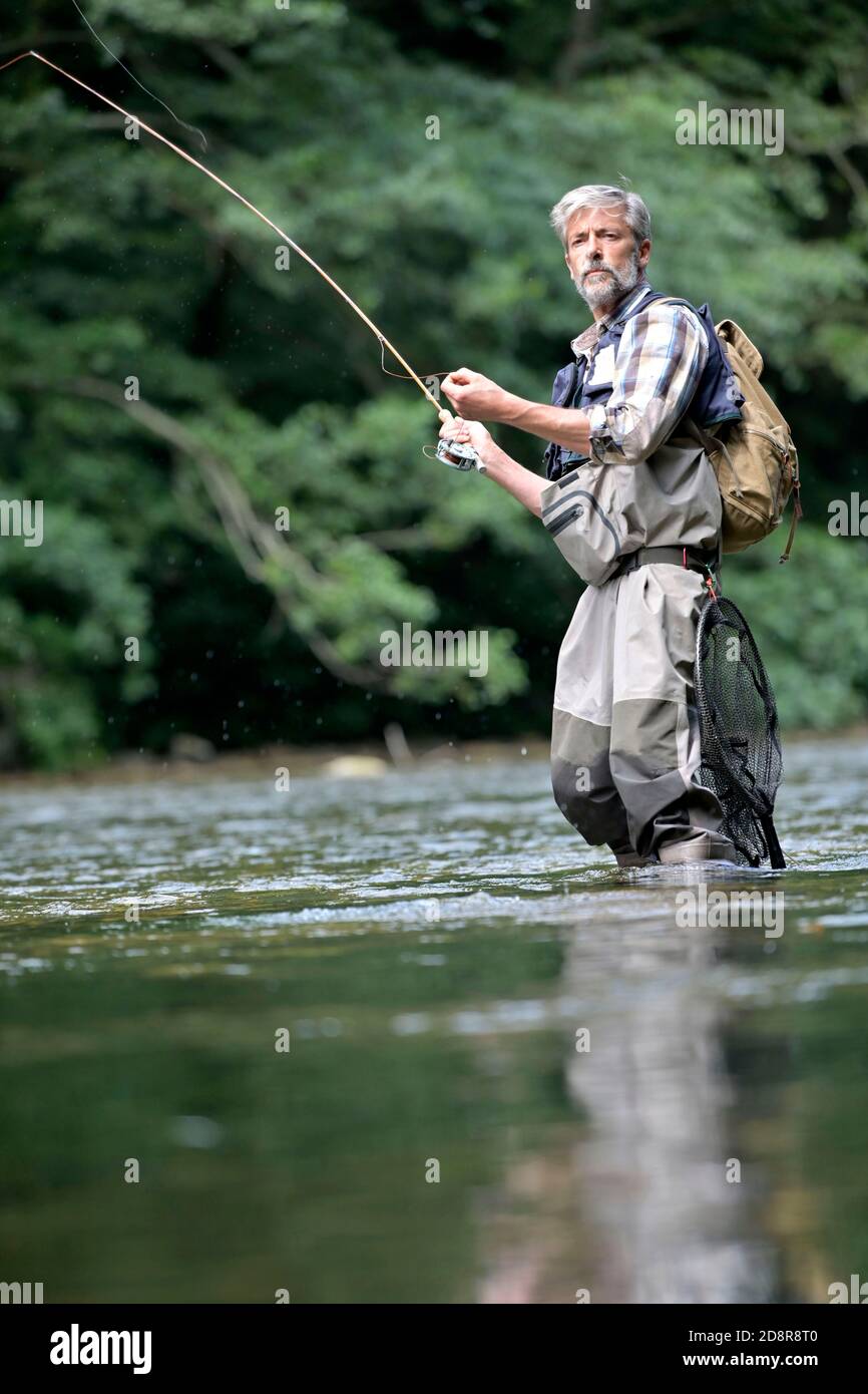 Man fly fishing in the summer in a beautiful river with clear water ...