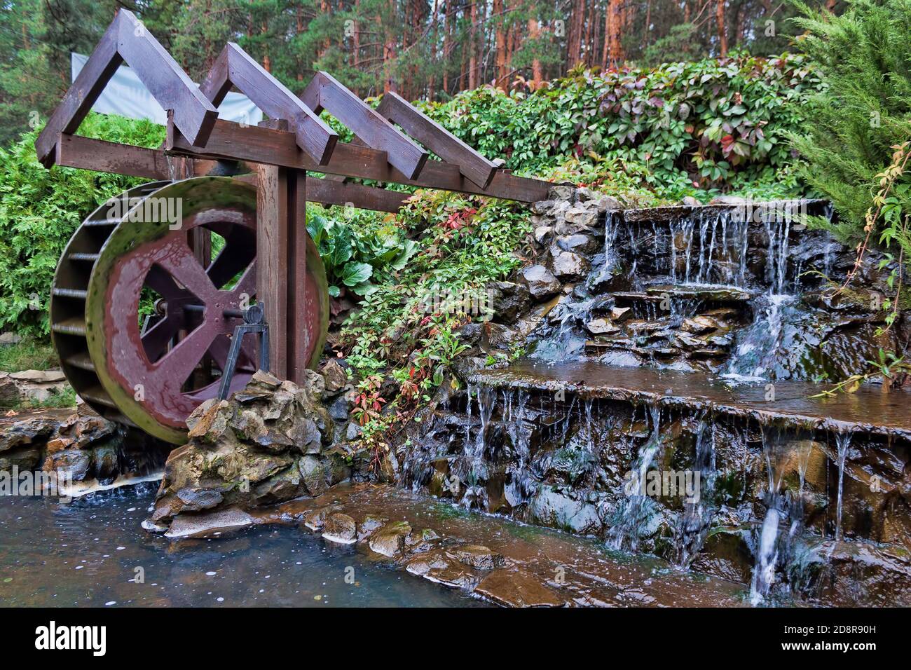 A small watermill next to a small artificial waterfall in the forest ...