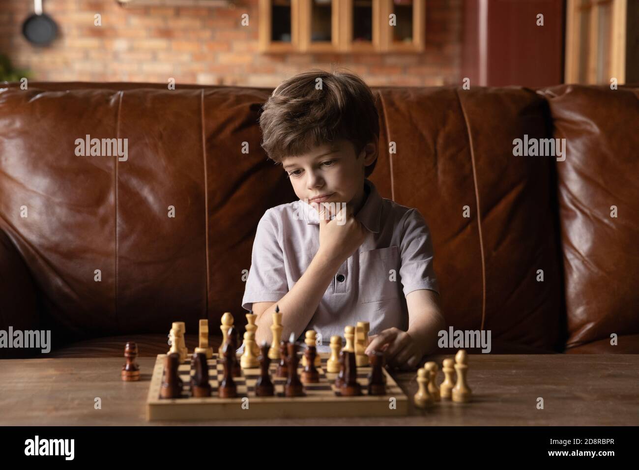 Pensive little boy play chess at home Stock Photo - Alamy