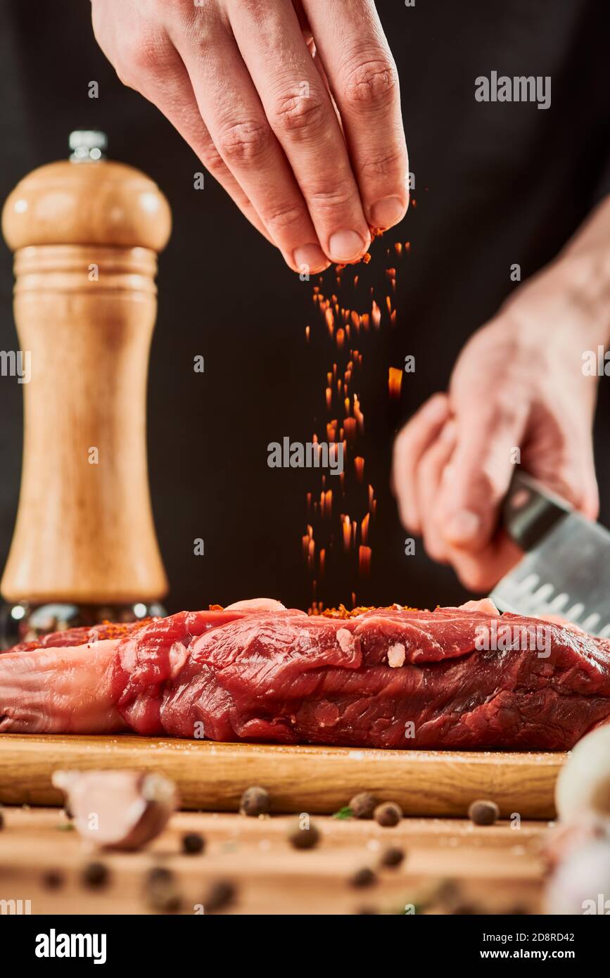 Hand sprinkles chili pepper onto raw meat, close-up shot Stock Photo ...