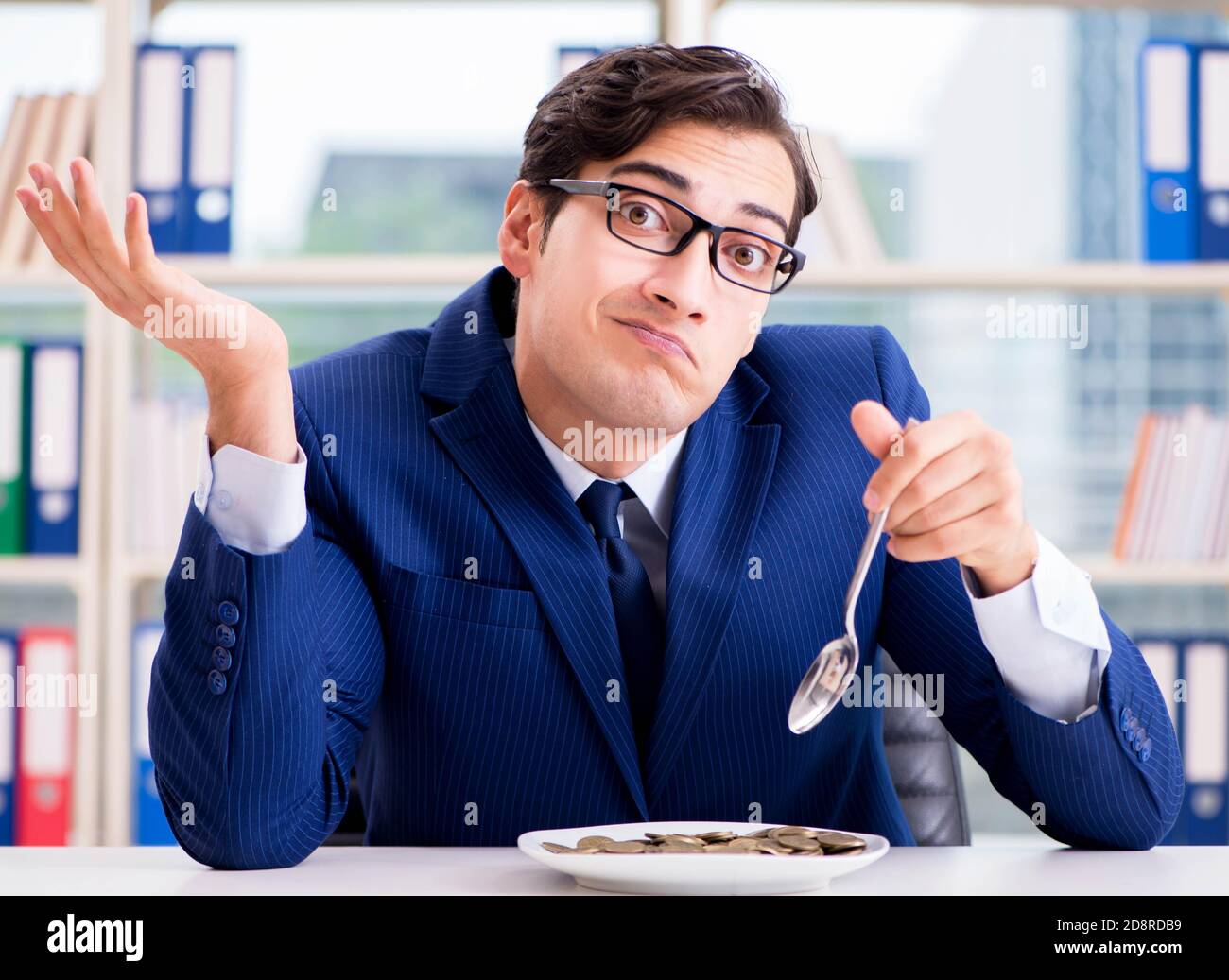 The funny businessman eating gold coins in office Stock Photo - Alamy