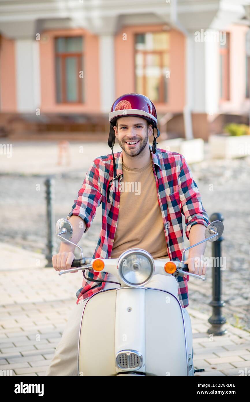 Man wearing a helmet riding his white scooter Stock Photo - Alamy
