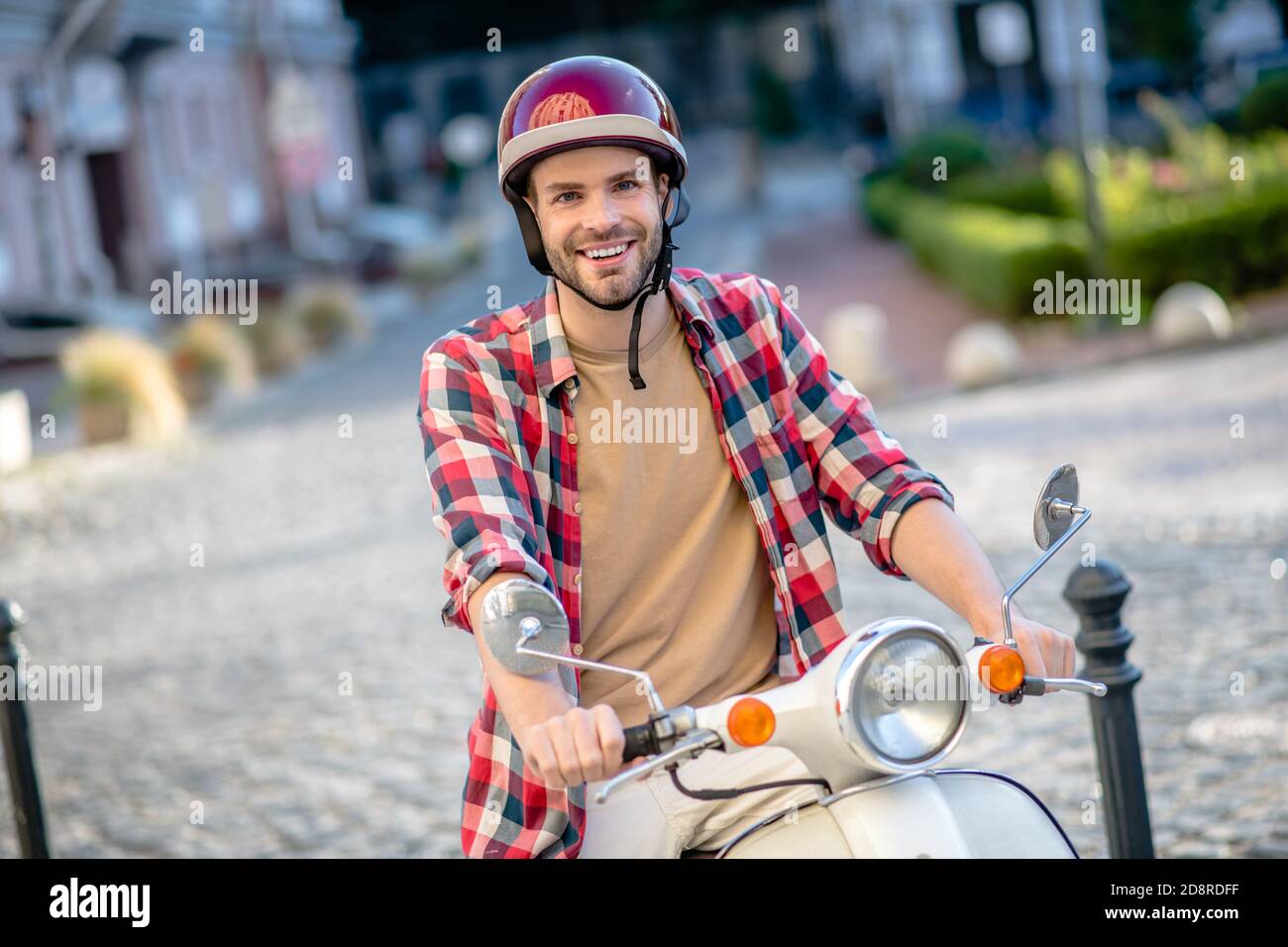 Man wearing a red helmet riding a scooter Stock Photo - Alamy