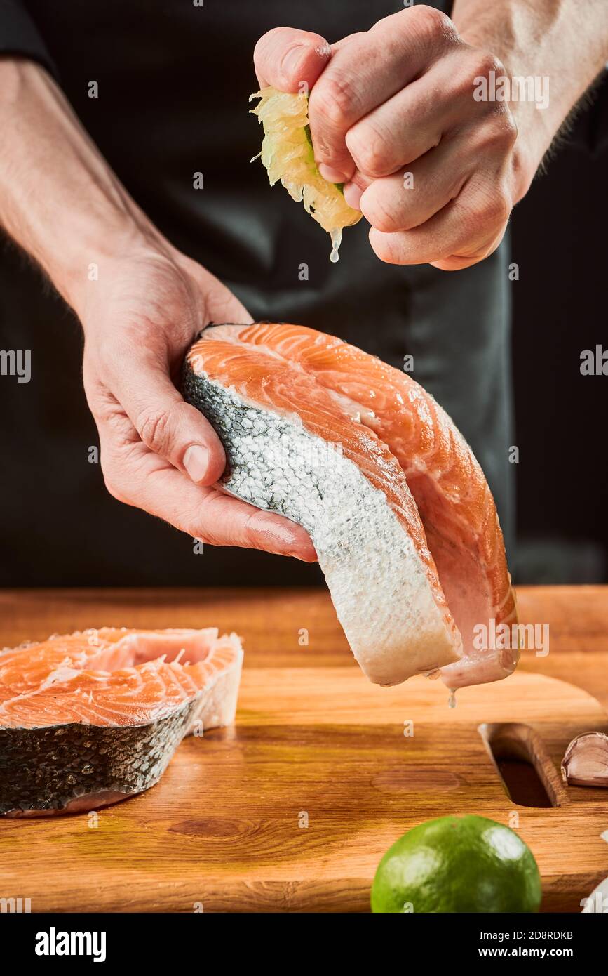 Man squeezing lime onto trout steak. Marinate fish for grilling Stock ...