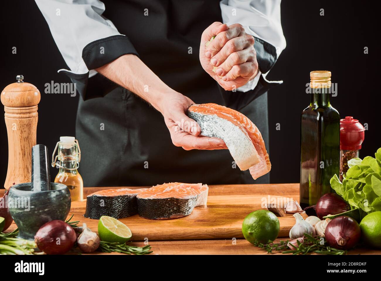 Chef squeezing lime over salmon steak. Cooking delicious fish dish ...