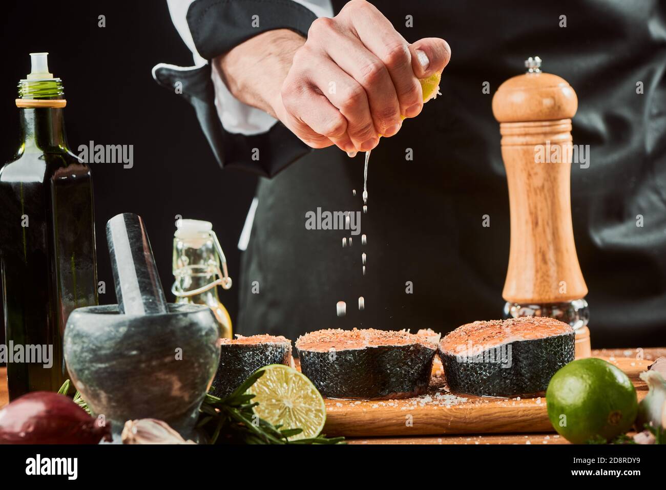 Professional chef squeezing lemon over salmon steaks Stock Photo - Alamy