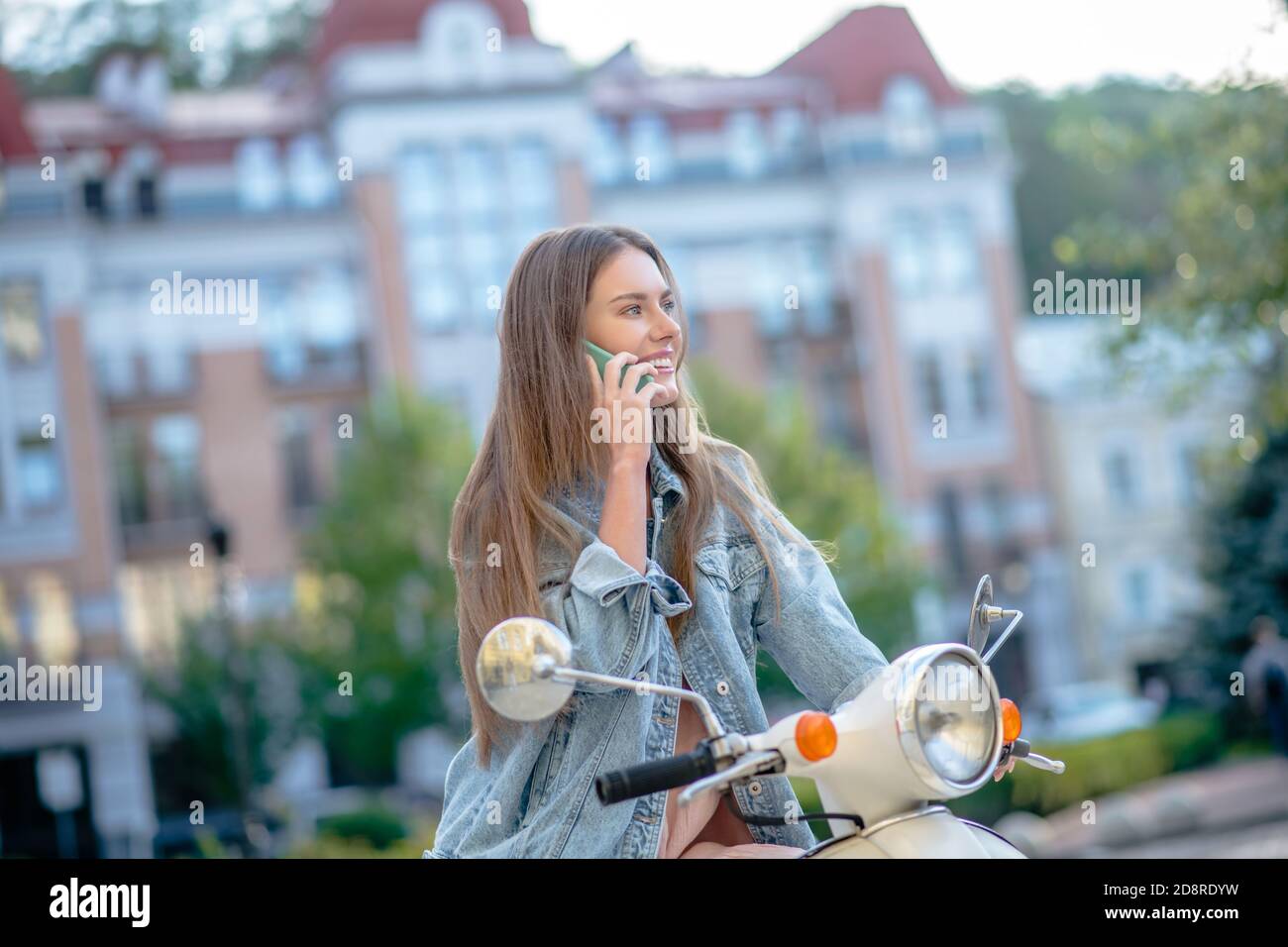 Woman riding scooter and making a phone call Stock Photo - Alamy