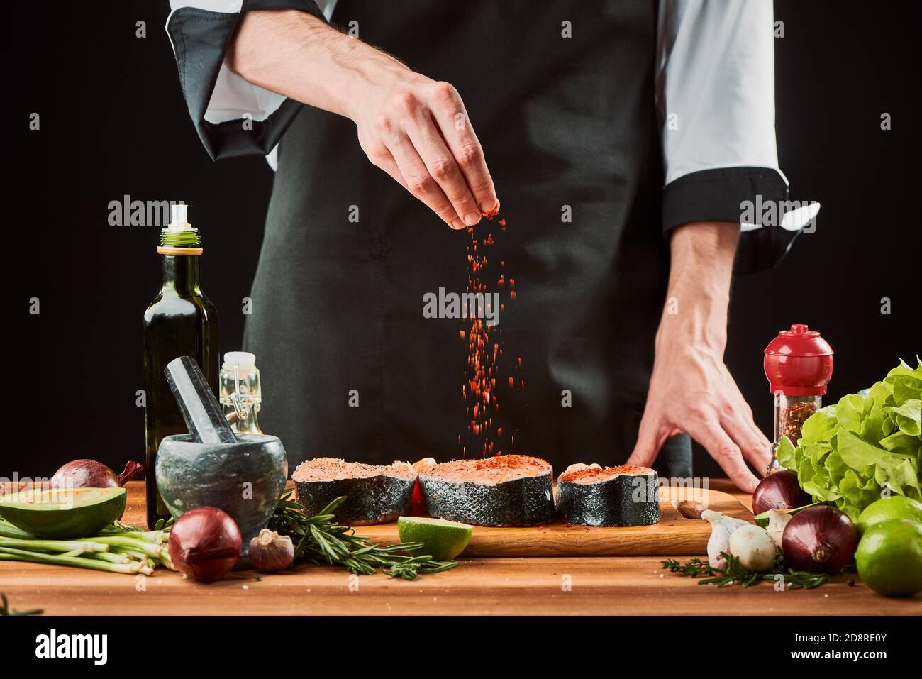 Hand sprinkling paprika onto salmon fillets. Cooking fish steak Stock ...