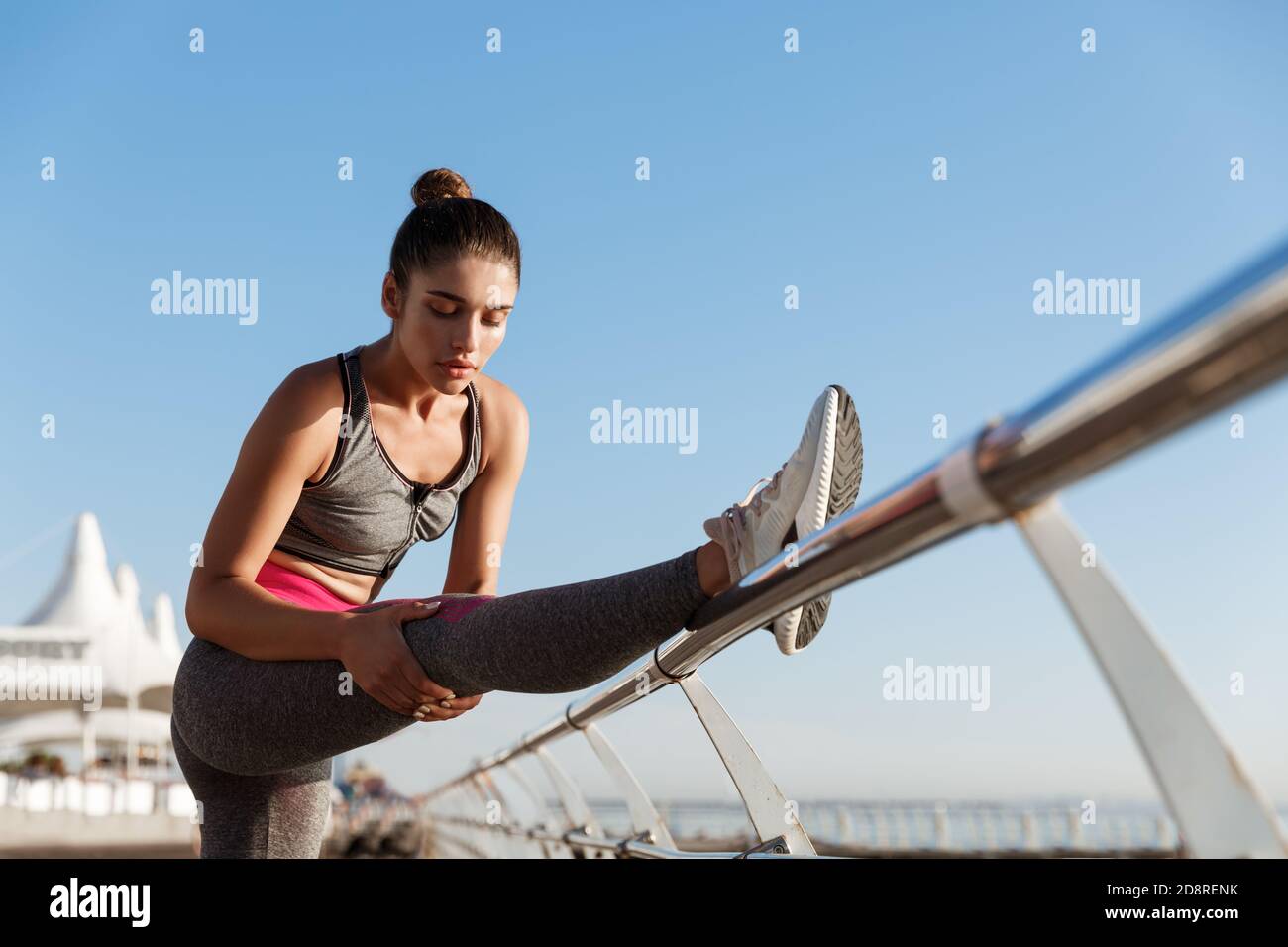 Young attractive female runner warming-up before training outdoors ...
