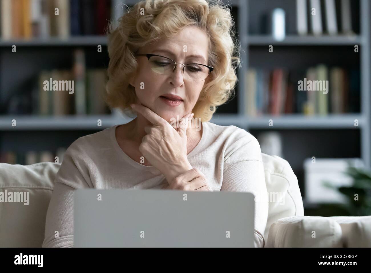 Thoughtful elderly woman looking at computer screen Stock Photo - Alamy