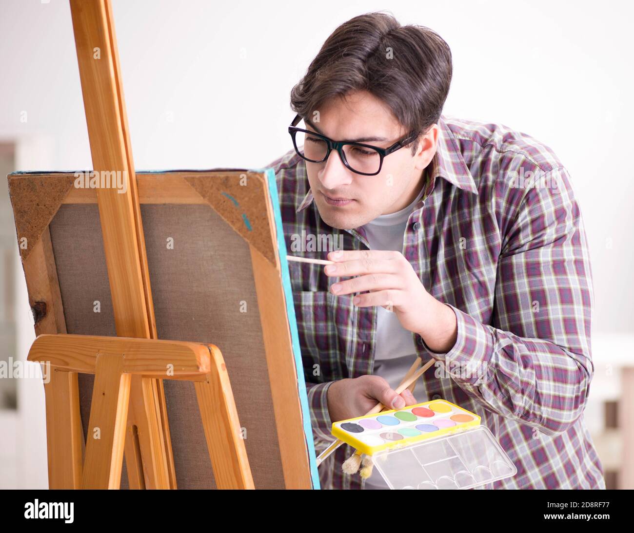 The young male artist drawing pictures in bright studio Stock Photo - Alamy