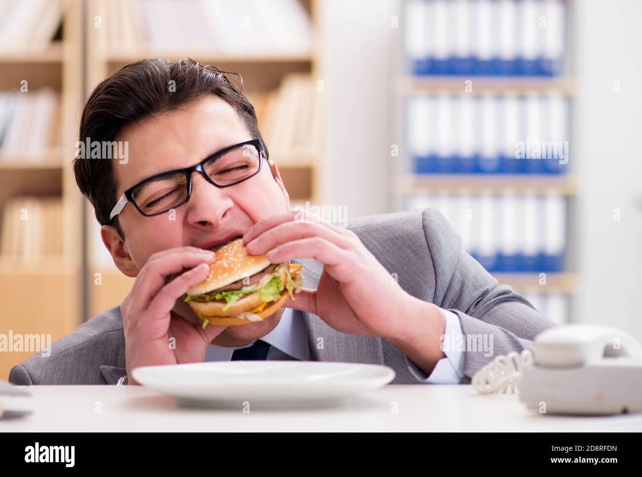 The hungry funny businessman eating junk food sandwich Stock Photo - Alamy