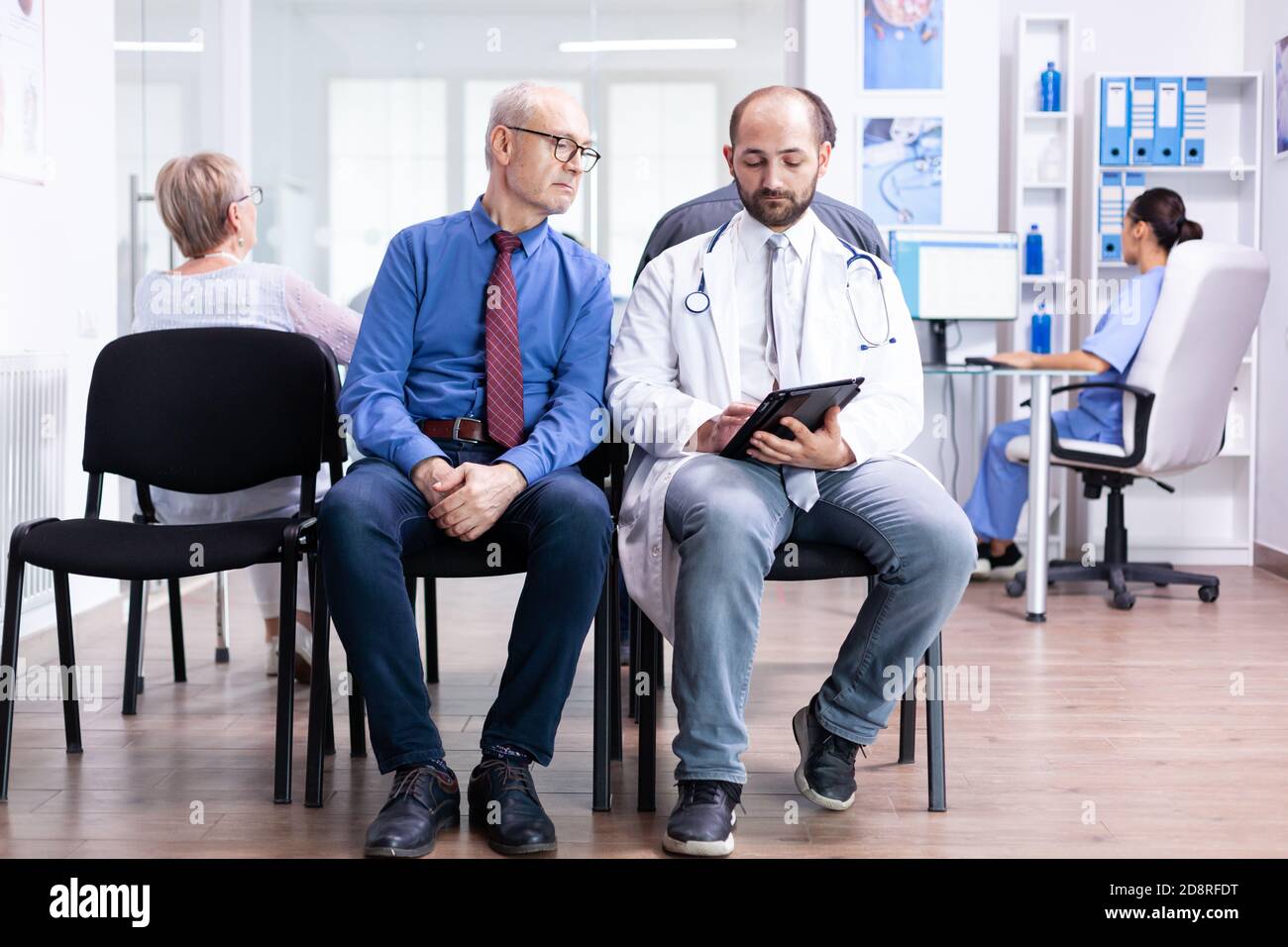 Doctor explaining test results to senior man in hospital waiting area ...