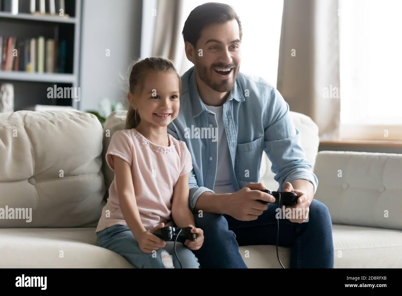 Smiling young father playing video games with daughter Stock Photo - Alamy