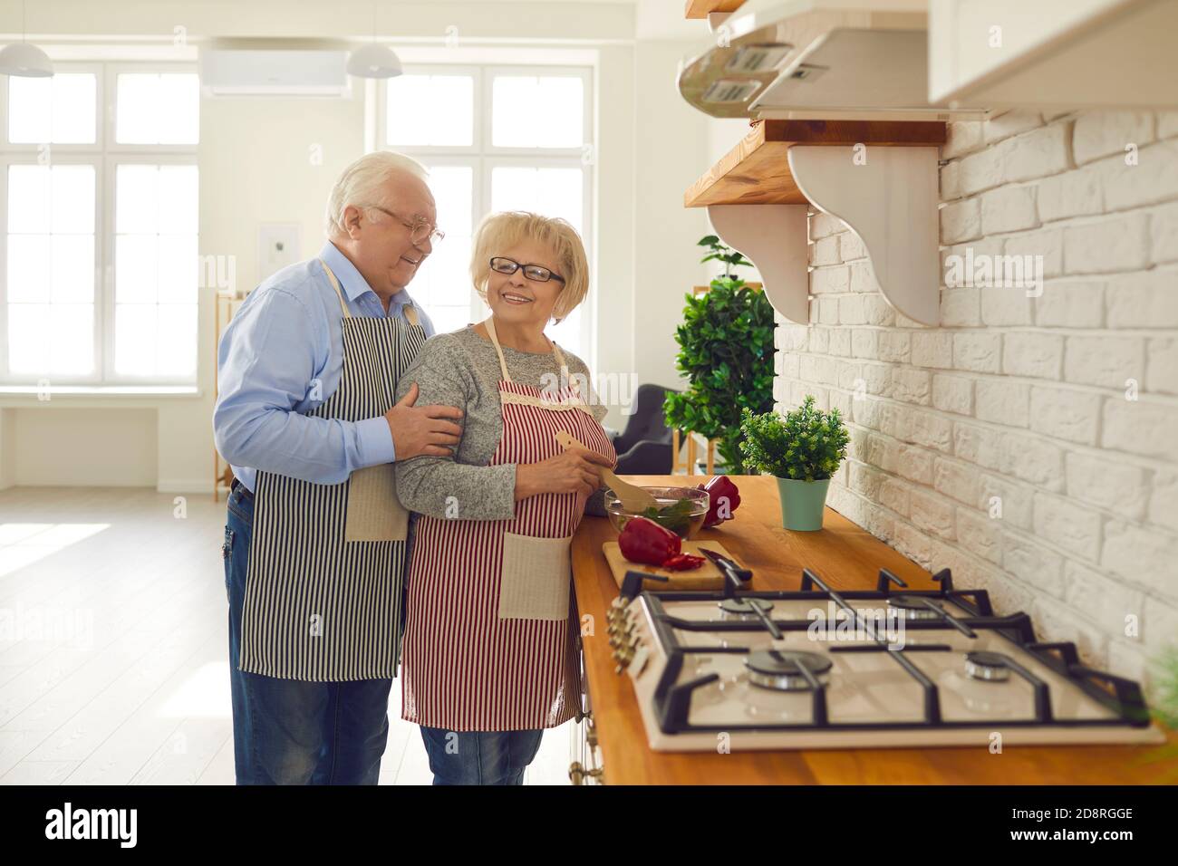 Happy senior couple cooking healthy veggie meal standing at countertop ...